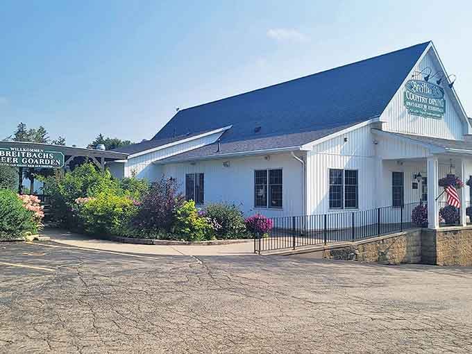 The classic white clapboard exterior of Breitbach's Country Dining welcomes visitors with its charming beer garden and colorful landscaping.