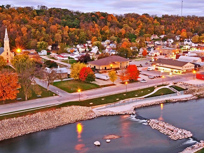 Autumn in Elkader paints the town in fiery hues, with the Turkey River flowing gently past historic buildings nestled among hills ablaze with color.