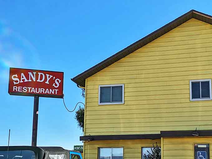 The iconic Sandy's sign stands tall against the Colorado blue sky, beckoning hungry travelers like a lighthouse for breakfast enthusiasts.