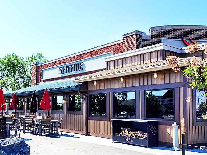 The restaurant's exterior blends rustic charm with modern sensibility, while those red umbrellas practically whisper, "Come sit awhile."