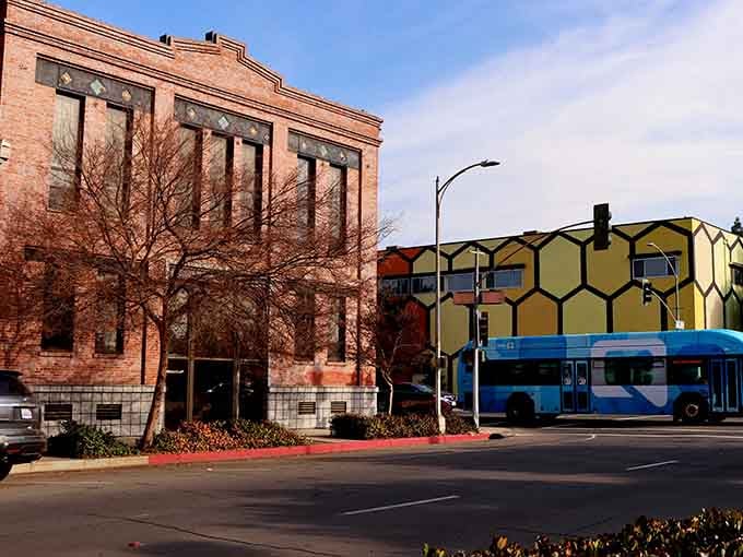 Historic brick buildings stand proudly alongside a colorful honeycomb-patterned structure, showcasing Fresno's blend of architectural preservation and modern creativity.