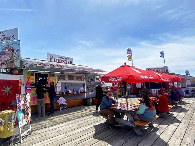 The holy grail of lobster rolls awaits under those bright red Coca-Cola umbrellas, where hungry pilgrims gather for Maine's ultimate seafood sacrament.