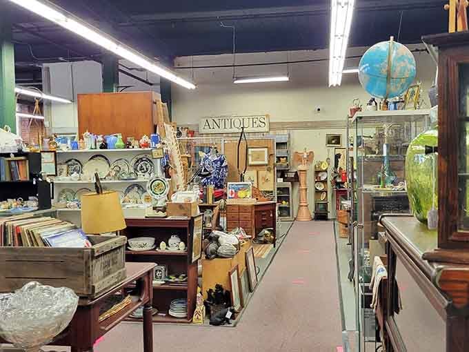 Aisles of carefully curated treasures stretch before you, with glassware, china, and a vintage globe inviting exploration at Acushnet River Antiques.