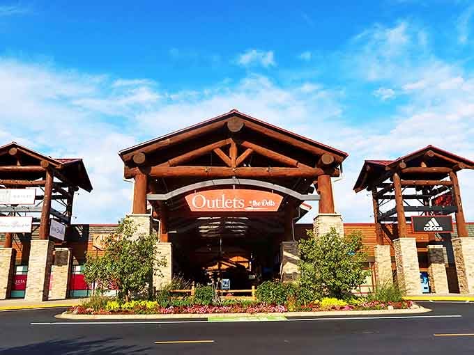 The impressive Northwoods-inspired entrance welcomes bargain hunters with rustic timber beams and meticulous landscaping, setting the tone for upscale outlet shopping.
