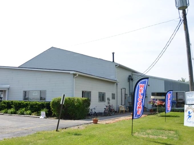 The unassuming exterior of Encore Thrift Store stands like a treasure chest waiting to be opened, with cheerful welcome banners fluttering in the Illinois breeze.
