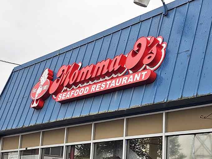 The bright red sign against the blue exterior isn't just eye-catching&mdash;it's a promise of seafood paradise waiting inside Momma O's in Anchorage.