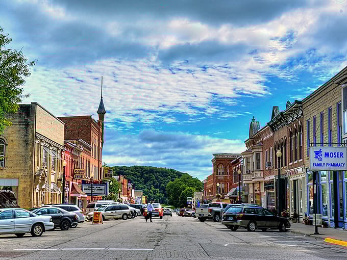 Elkader basks under clear blue skies, with the Turkey River flowing gently past charming historic buildings nestled among rolling hills.