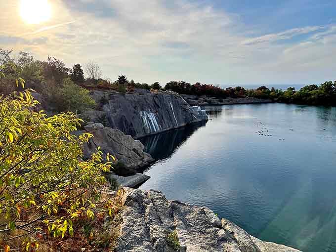 The quarry's sheer granite walls plunge into mirror-like waters, creating nature's own infinity pool where sky meets stone in perfect reflection.