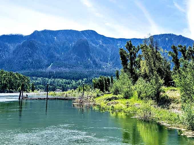 The tranquil waters of the Columbia River reflect the surrounding mountains, creating a mirror image that doubles the beauty of this scenic wonderland.