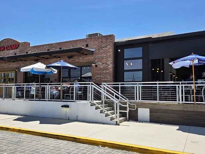 Blue umbrellas dot the spacious waterfront deck, offering shaded spots to savor fresh catches while enjoying the San Sebastian River views.