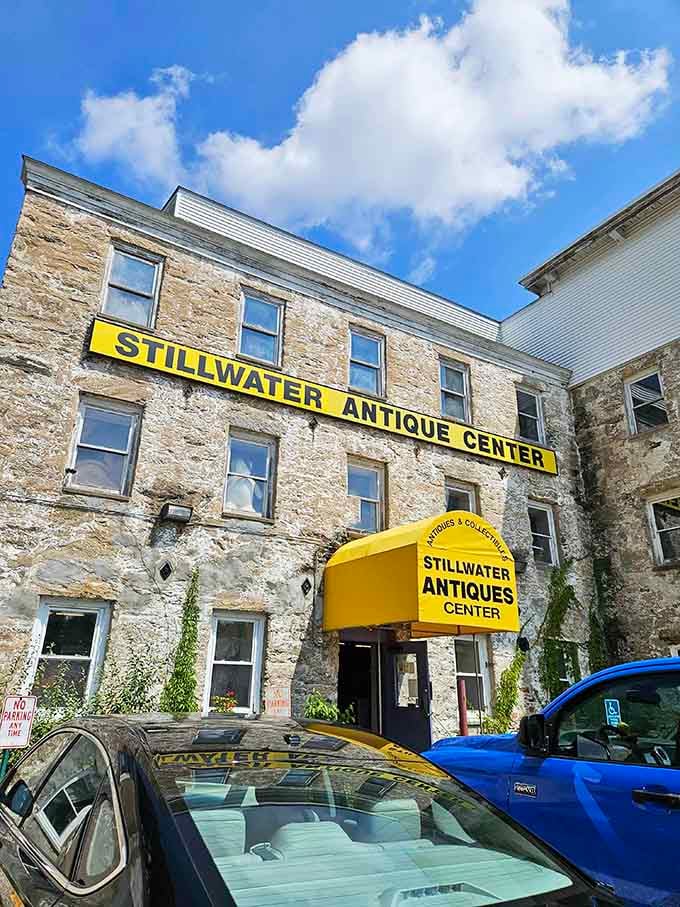 The stone facade of Stillwater Antique Center stands like a fortress of forgotten treasures, its bright yellow sign a beacon to collectors and the curious alike.