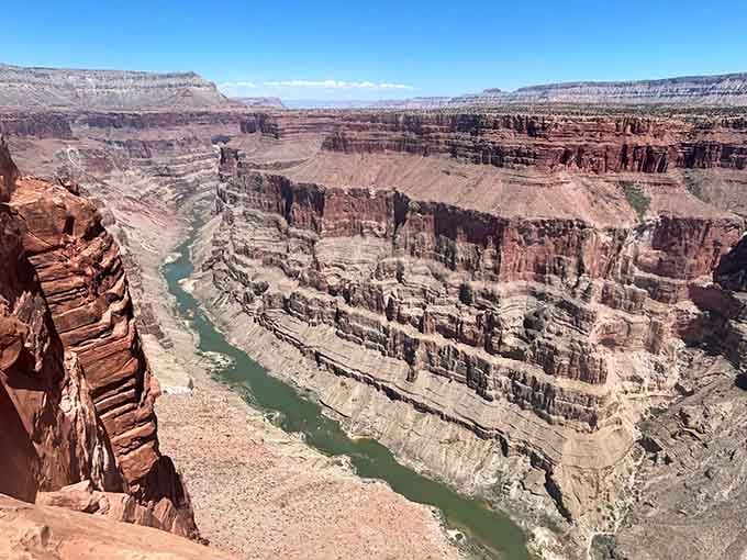 Three thousand feet straight down to where the Colorado River carves its eternal masterpiece through ancient stone.