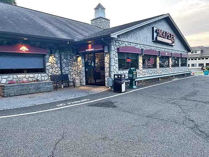 The stone facade of Maples Family Restaurant stands as Middlebury's beacon of breakfast bliss, its iconic red sign promising comfort food paradise within.