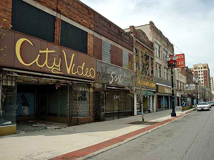 The faded storefronts tell stories of a thriving past now locked behind gates and forgotten windows.