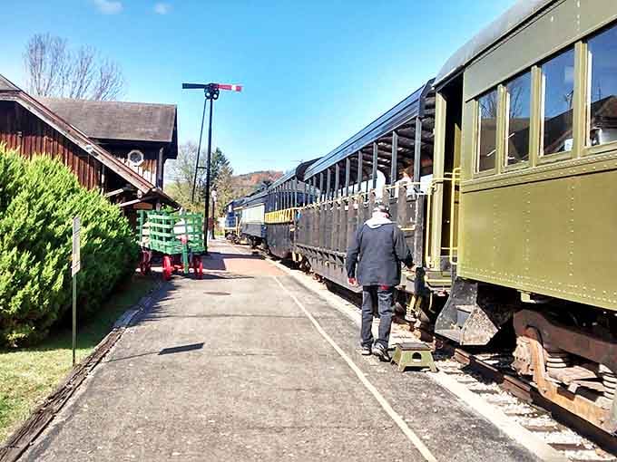 A railway volunteer prepares the historic train for departure while passengers eagerly await their nostalgic adventure.