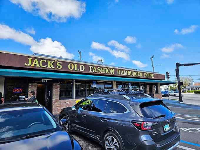 The blue and yellow sign of Jack's Old Fashion Hamburger House stands like a beacon of burger hope against the Florida sky, promising delicious simplicity in a world of culinary complications.