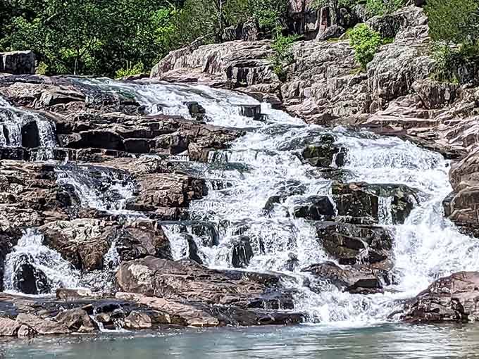 Nature's staircase tumbles over billion-year-old rhyolite like a liquid symphony in pink and gray stone.