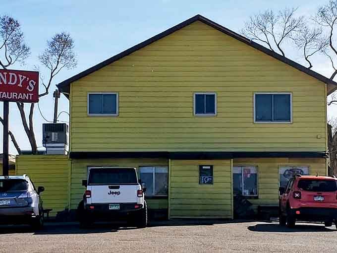 The bright yellow exterior of Sandy's Restaurant stands like a cheerful beacon against the Colorado sky, promising comfort food treasures within those humble walls.
