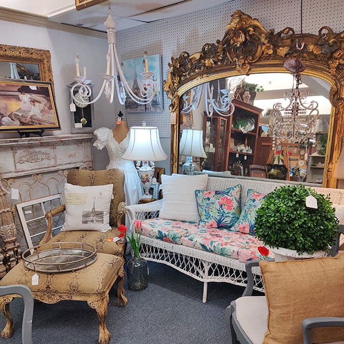 A meticulously arranged vendor booth showcases elegant furniture, ornate mirrors, and vintage decor&mdash;a perfect stage set from another era.