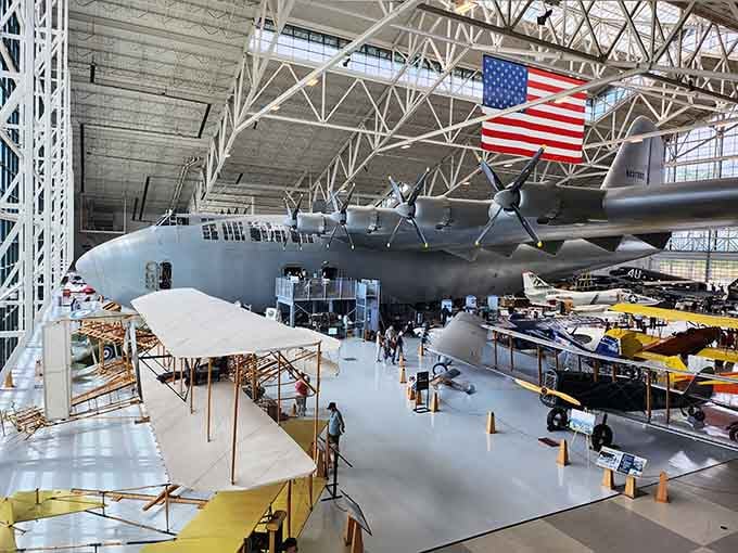 That massive wooden giant suspended overhead is the legendary Spruce Goose, making your garage project look adorably modest.