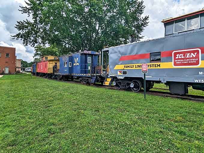 A colorful lineup of vintage train cars rests on the tracks, like a life-sized toy set waiting for grown-ups to rediscover their childhood wonder.