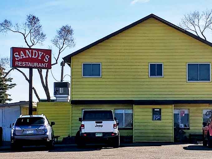 The iconic Sandy's sign stands tall against the Colorado blue sky, beckoning hungry travelers like a lighthouse for breakfast enthusiasts.