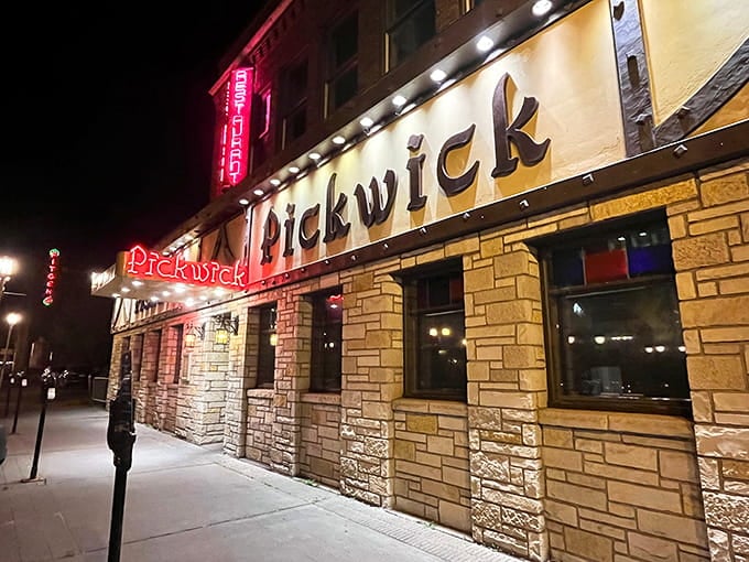 That glowing red neon against stone walls creates the kind of timeless street presence that makes you slow down.
