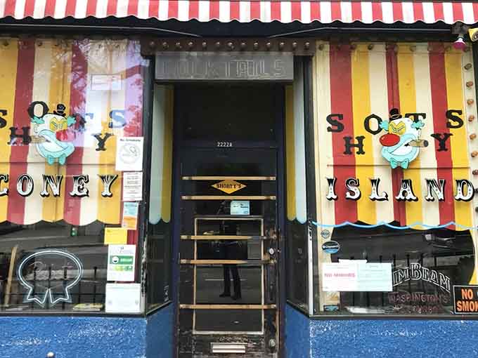 That candy-striped facade isn't selling peppermint sticks, it's your gateway to hot dog heaven and pinball paradise.