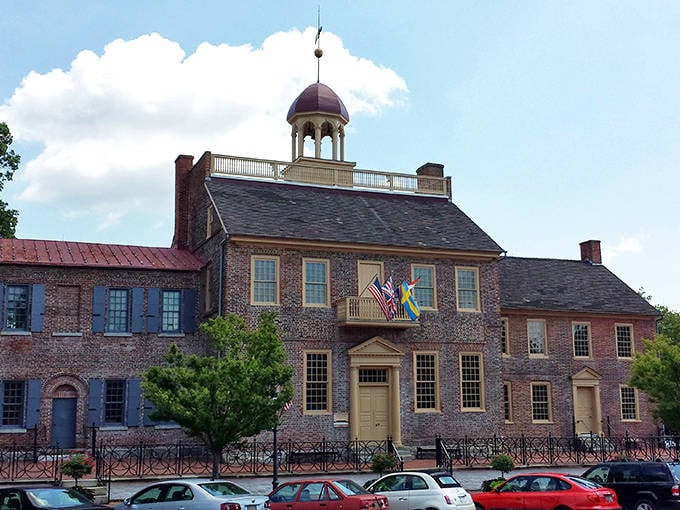 Colorful flags wave proudly above historic brick buildings on this charming New Castle street, where colonial architecture meets modern life.