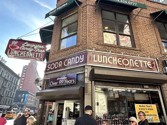 The "Soda Candy Luncheonette" sign has watched the neighborhood transform while staying exactly the same, bless it.
