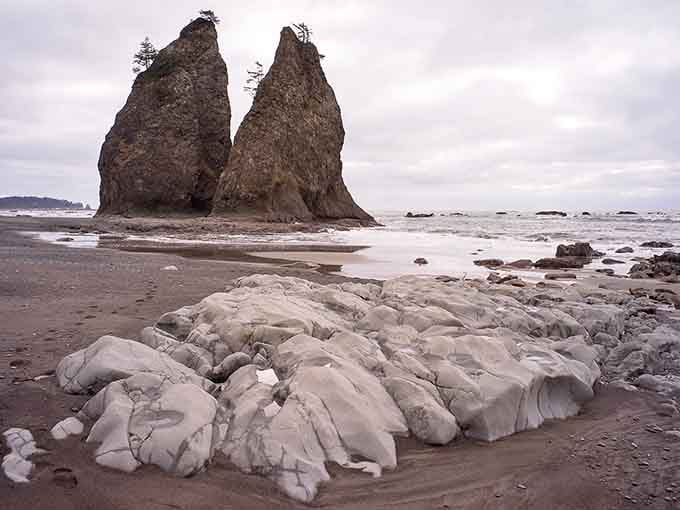 Sea stacks stand sentinel in calm waters, their twin peaks creating one of the beach's most recognizable landmarks.
