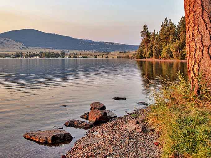 Mother Nature's masterpiece unfolds at the shoreline, where rocky outcrops meet crystal waters and distant mountains paint the perfect backdrop for contemplative moments.