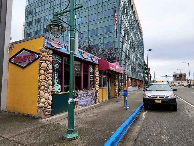 The vibrant yellow exterior of Humpy's stands out against Anchorage's urban backdrop like a cheerful beacon for hungry travelers seeking Alaskan culinary treasures.