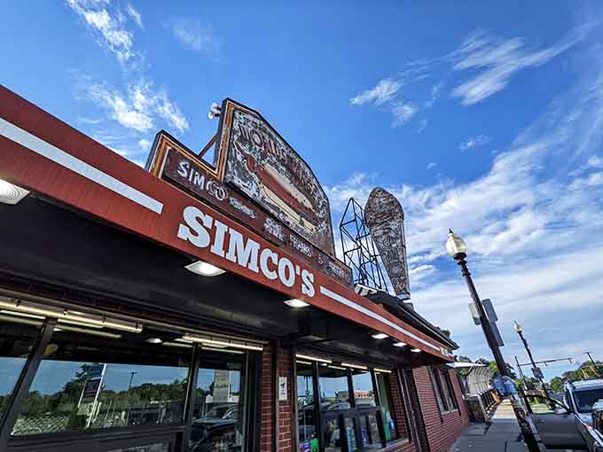 Looking up at Simco's against a gorgeous sky, where weathered signs tell stories of decades spent perfecting the hot dog.