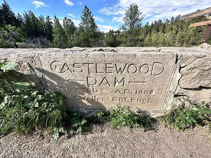 Carved stone commemorates the dam's construction, a permanent marker of engineering dreams that couldn't quite hold.