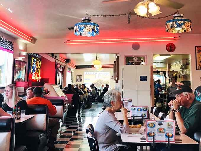 Where strangers become neighbors over coffee and pie. The red neon glow makes everyone look like they're starring in their own Edward Hopper painting.