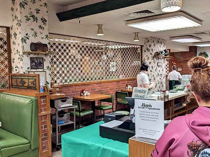 The lattice dividers and green booths create dining areas that feel private yet connected to the restaurant's buzzing energy.