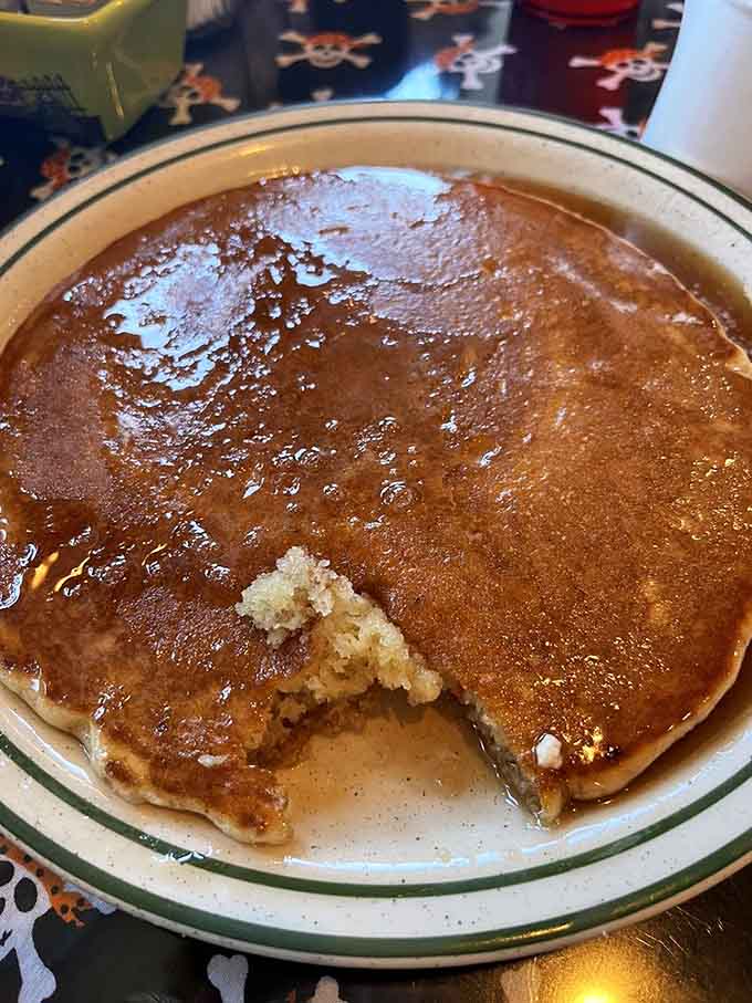 A pancake swimming in syrup with a pat of butter melting on top, breakfast perfection captured in one glorious plate.