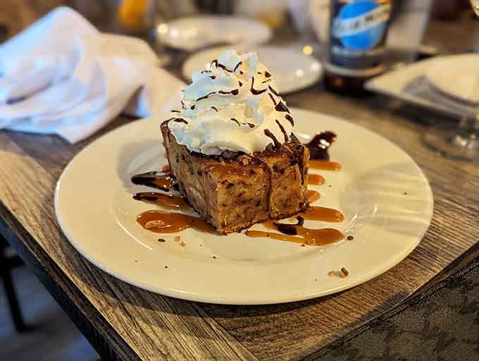 Bread pudding topped with whipped cream and drizzled with sauce, because restraint is overrated at brunch.