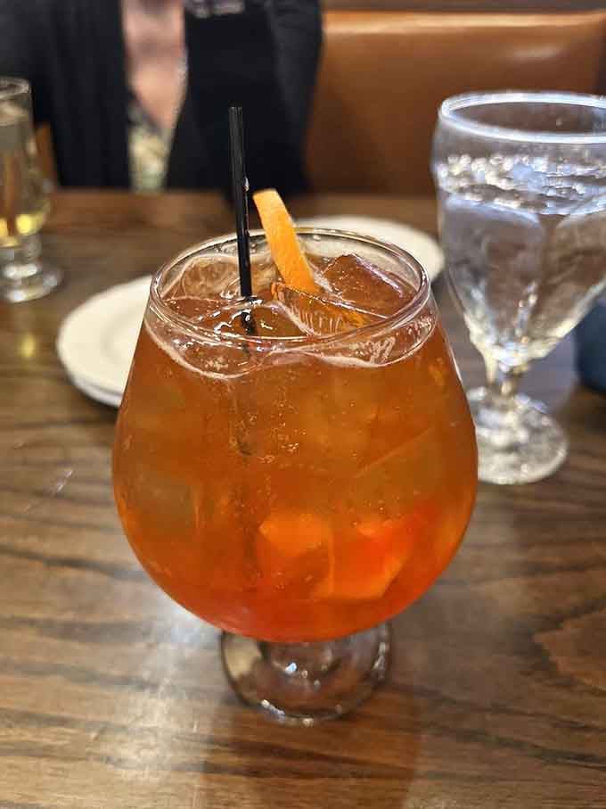 A perfectly crafted old fashioned glows amber in its glass, garnished with orange and ready to start your meal right.