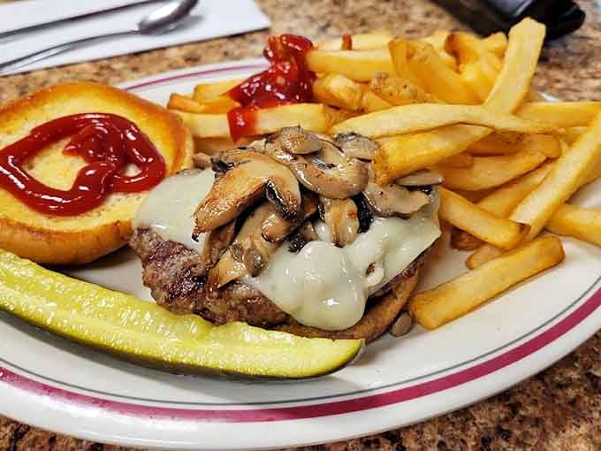 Mushroom-topped burger with fries: classic American diner fare executed exactly the way your taste buds remember and crave.