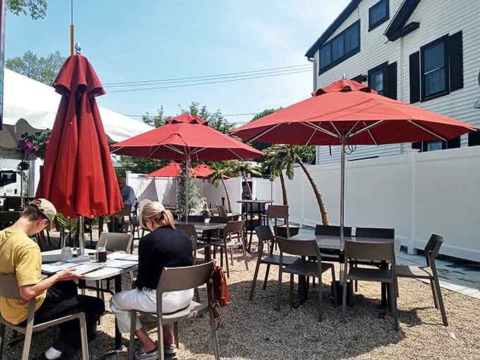 The outdoor patio offers a casual oasis where red umbrellas provide shade for serious seafood contemplation.