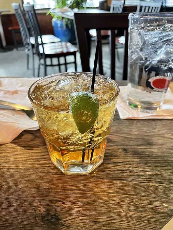 A perfectly poured whiskey with lime, catching the light like liquid gold on a well-worn table.