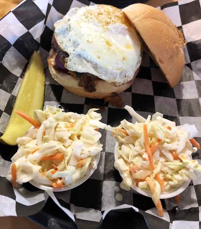 That fried egg sits atop the burger like a golden crown, with coleslaw providing the perfect crunchy contrast.