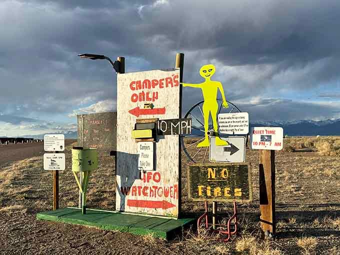 Directional signs point toward campers and alien encounters, treating both with equal navigational importance and enthusiasm.