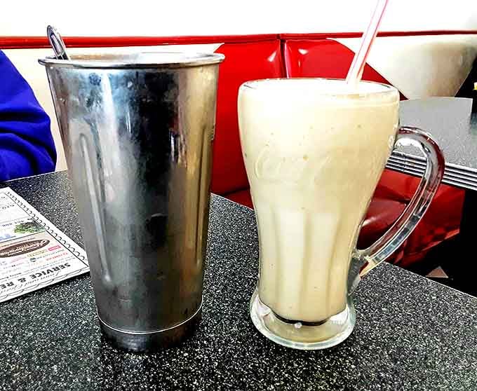 The classic diner milkshake setup&mdash;metal mixing cup alongside the finished masterpiece. It's not just a drink, it's a commitment.