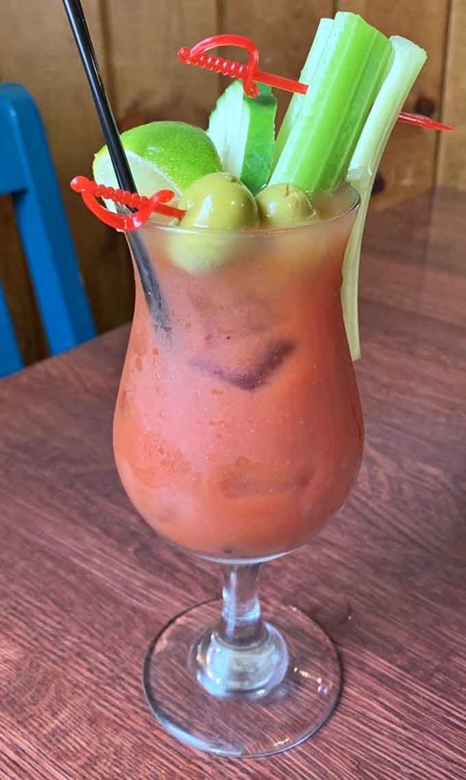 A Bloody Mary garnished with celery and olives that's practically a meal itself, perfect for weekend brunch adventures.