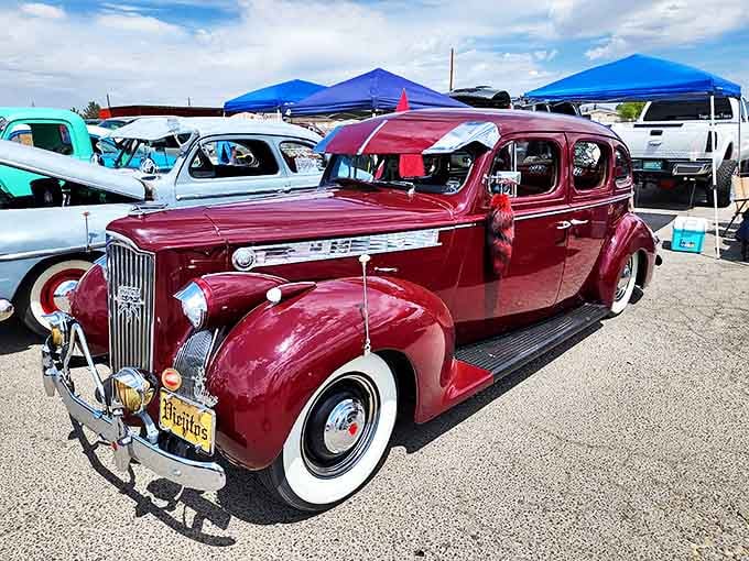 A gleaming vintage Packard holds court among lesser vehicles. This crimson beauty isn't just transportation&mdash;it's a time machine with whitewalls.