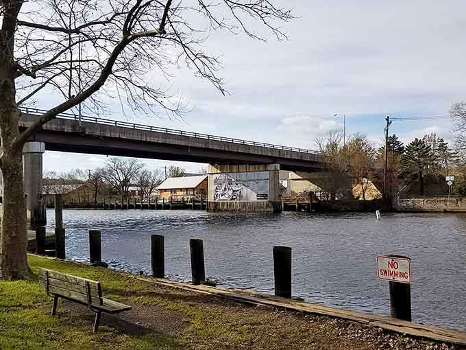 The river flows peacefully past the bench, creating the perfect spot for contemplating absolutely nothing at all.