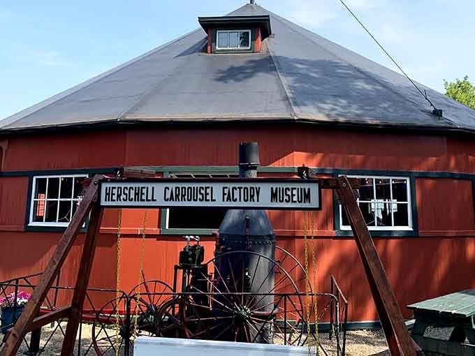 The round barn's distinctive shape and weathered red paint tell stories of carousel-making history and craftsmanship.